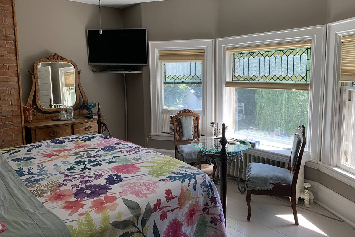 Quarto com cama, penteadeira, cômoda e televisão.