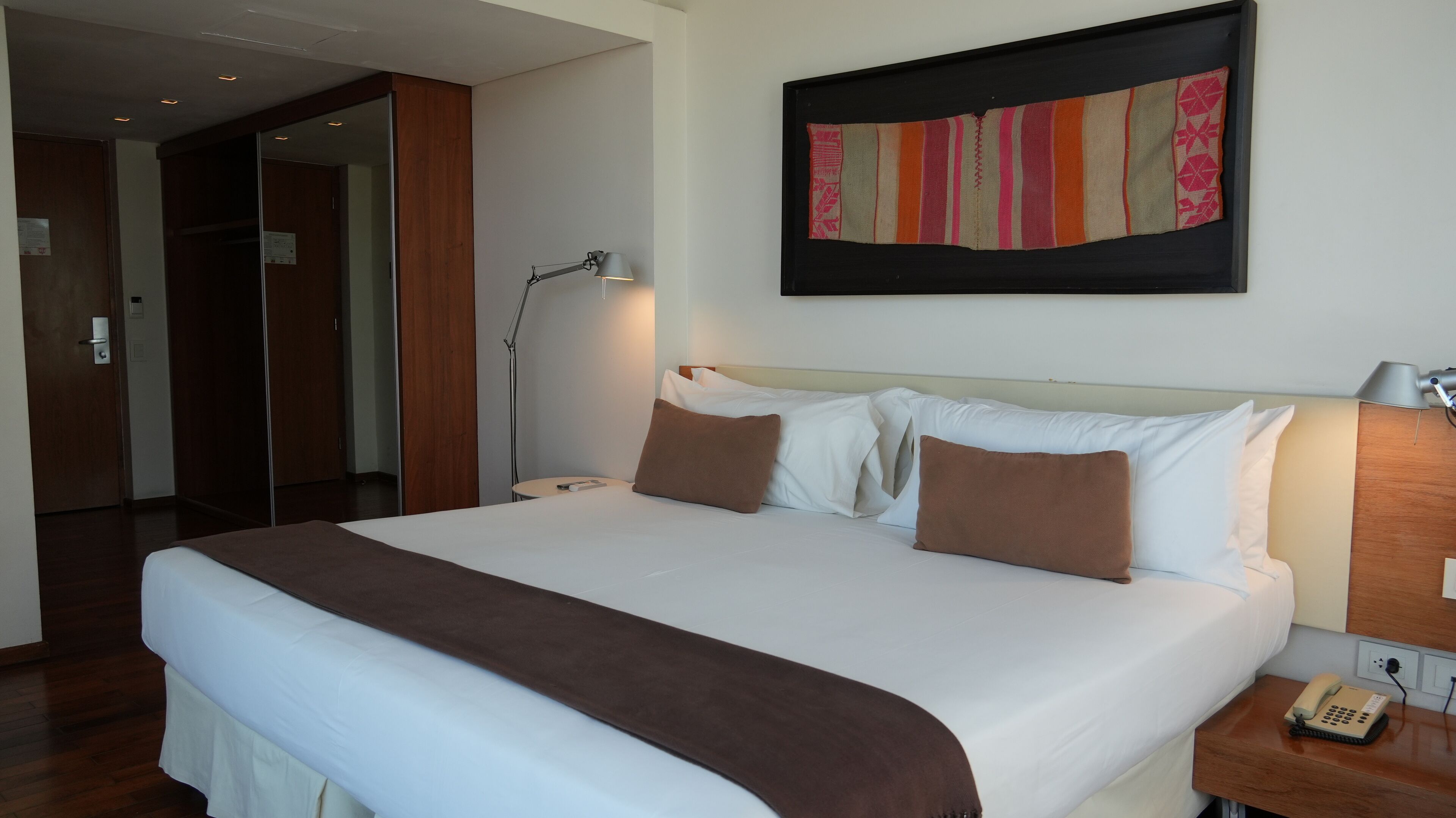 Quarto de hotel com uma cama grande, um telefone de mesa e um abajur.