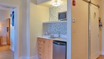 Uma cozinha compacta com lava-louças, micro-ondas e painel de azulejos.