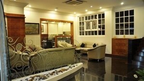 Uma sala de estar ampla com sofá, poltronas, mesa de centro e um lago decorativo com peixes.