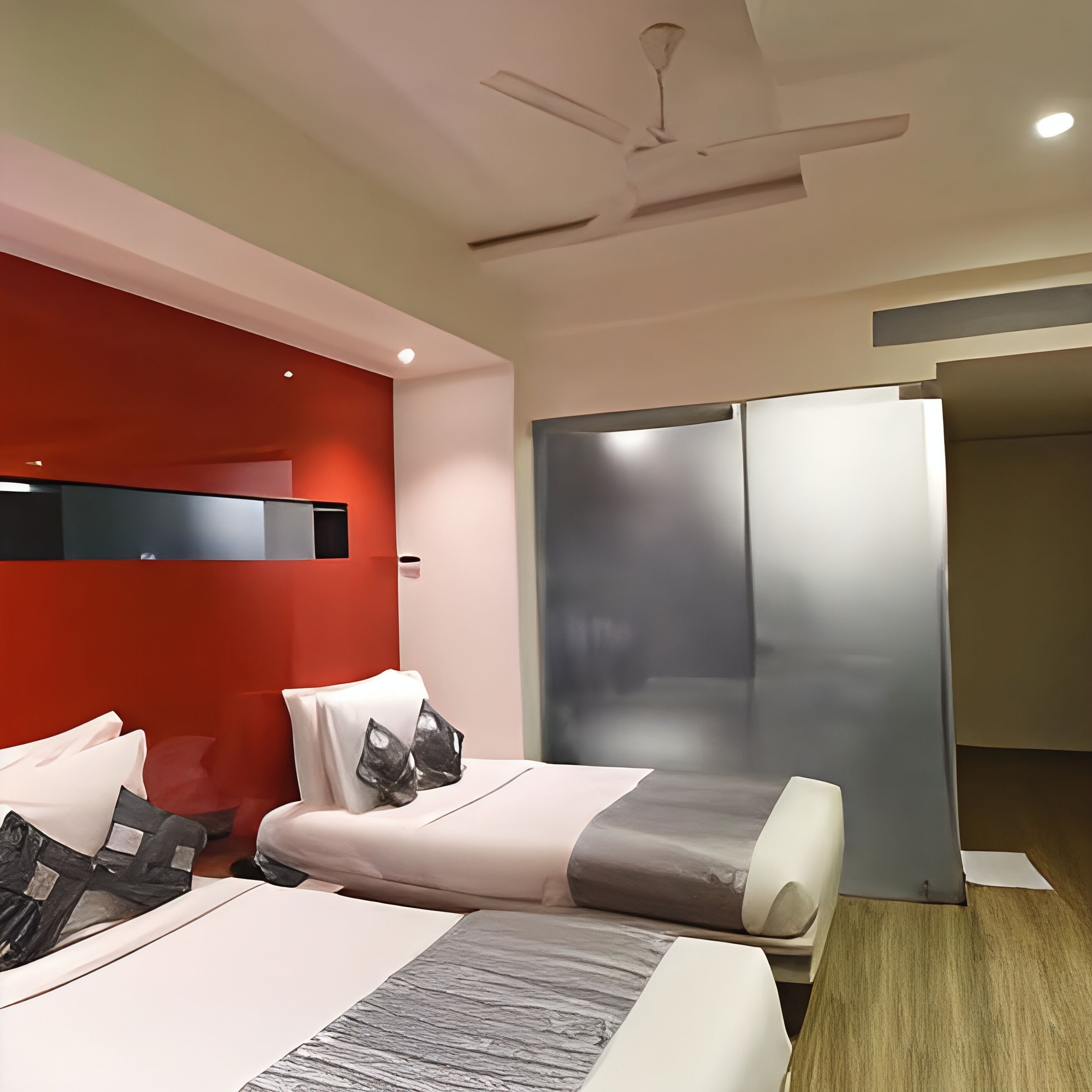 Quarto de hotel moderno com cama, parede de destaque vermelha, ventoinha no teto e guarda-roupa com portas deslizantes.
