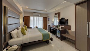 Quarto de hotel com cama, escrivaninha, televisão e frigobar.