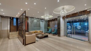 Um lobby moderno com um sofá, cadeiras, uma mesa de centro e um lustre.
