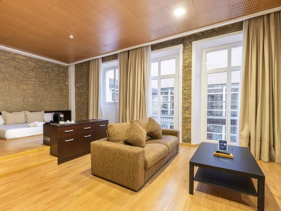 Uma sala moderna com sofá, mesa de centro, cômoda e cama.