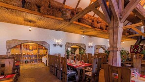 Um restaurante rústico com mobiliário de madeira, paredes de pedra e teto de palha.