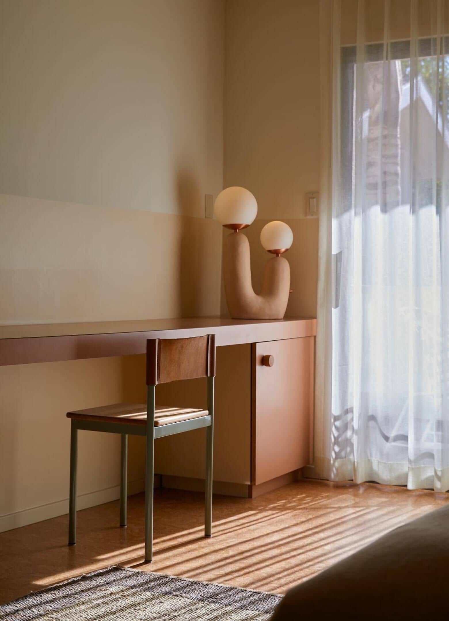 Quarto moderno com escrivaninha de madeira, uma cadeira e design de luminária exclusivo.