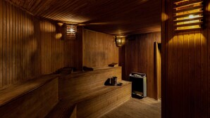 Uma sauna de madeira com bancos e mesa para sauna, equipada com um aquecedor e uma pequena pia.