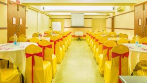 Uma sala de conferência com fileiras de mesas e cadeiras, cada cadeira amarela adornada com fitas vermelhas.
