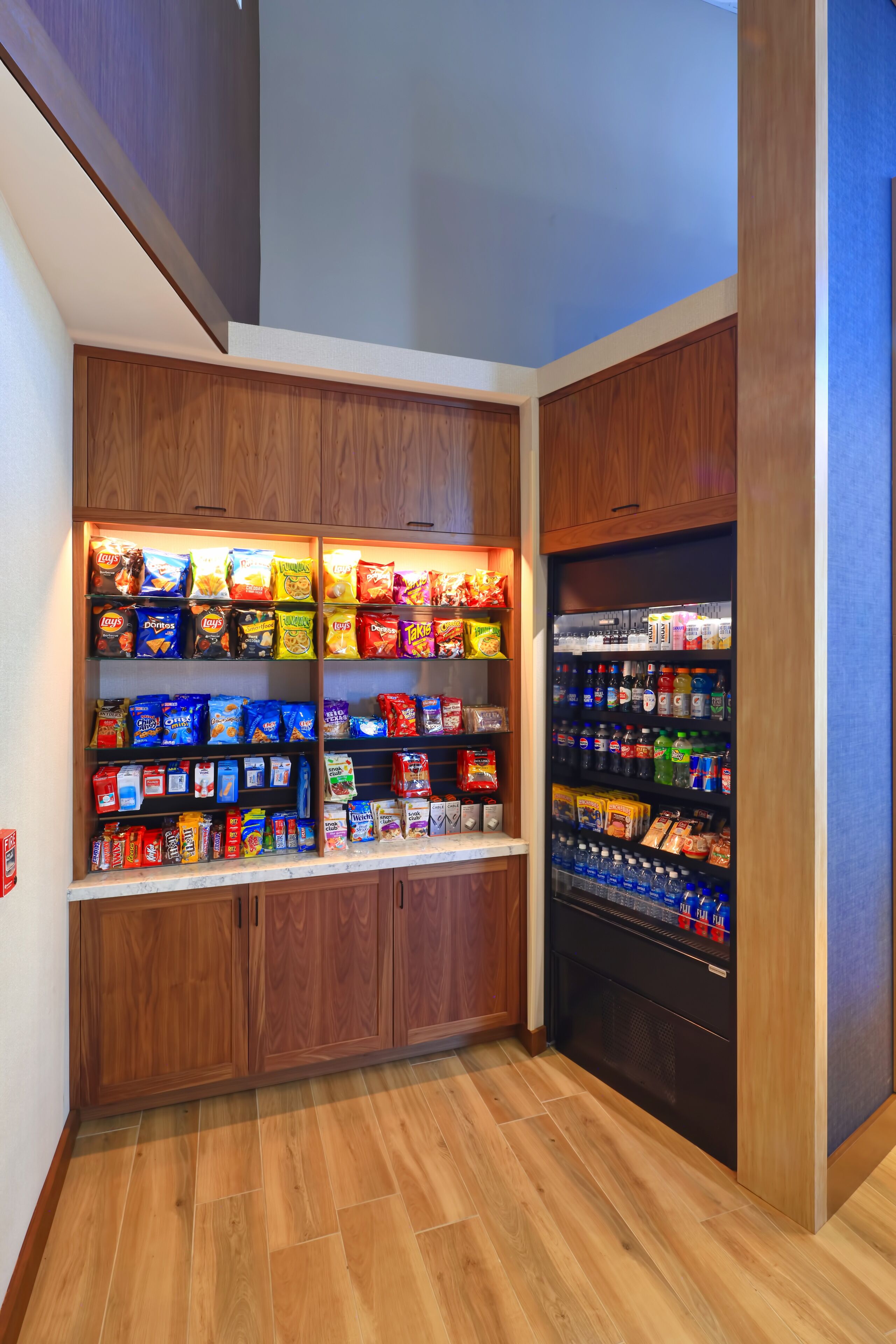 Uma área de venda automática com diversos prateleiras de lanches e um refrigerador de bebidas.