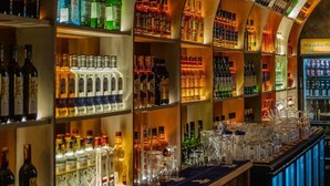 Um bar com prateleiras cheias de garrafas de bebidas e copos.