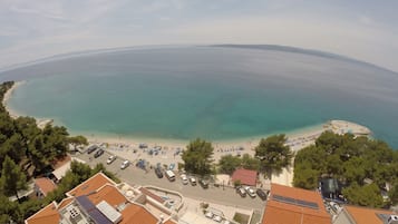 Uma cidade costeira com praia, edifícios com telhados de cerâmica vermelha e carros estacionados.