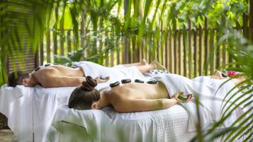 Um espaço de spa com mesas de massagem, plantas verdes e uma cerca de bambu.