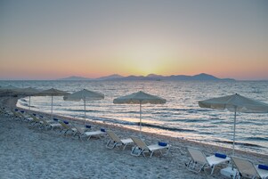 Na praia, espreguiçadeiras, guarda-sóis de praia, toalhas de praia 