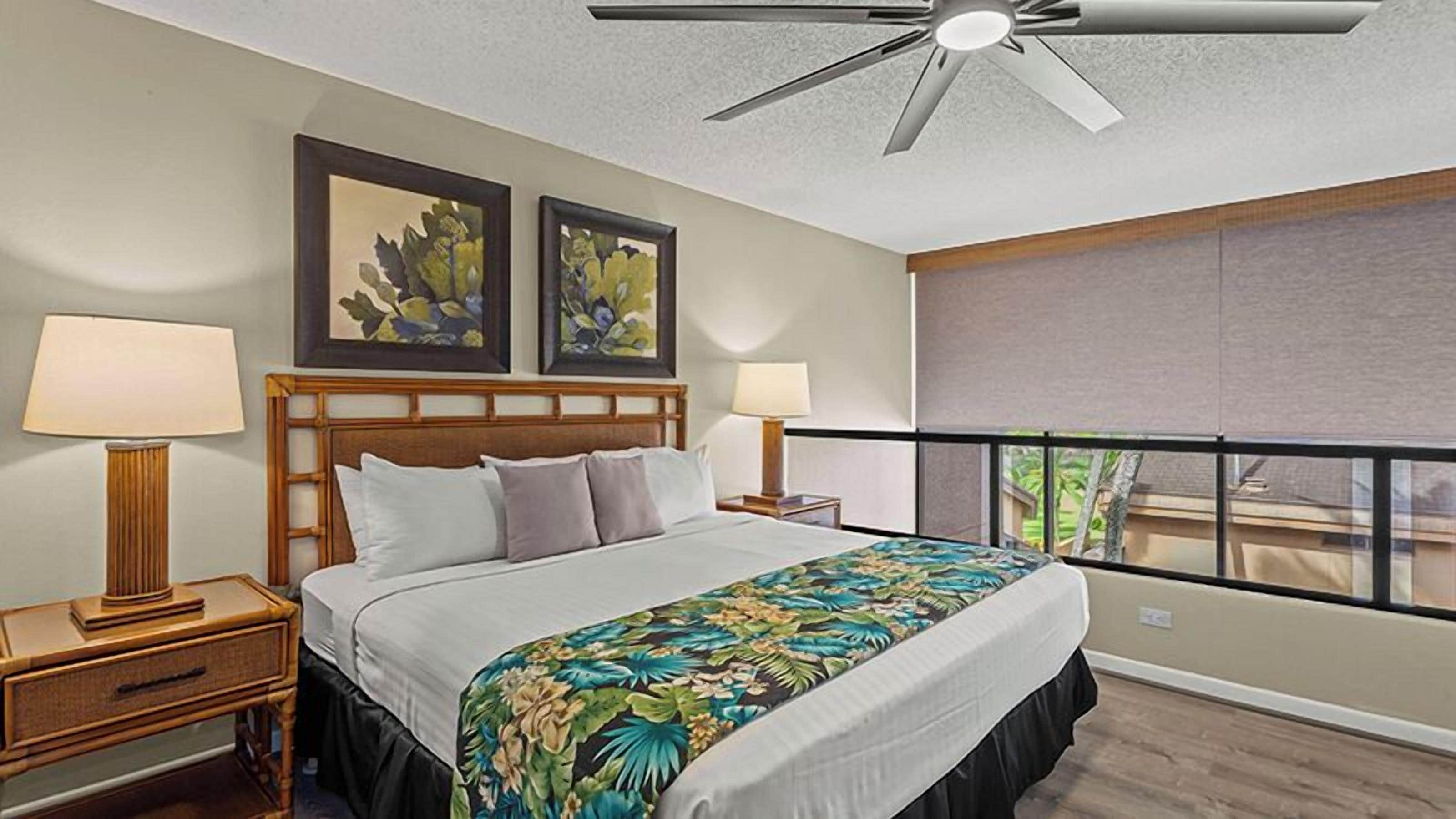 Quarto de hotel com cama, duas mesas de cabeceira, ventoinha no teto e janela com vista.