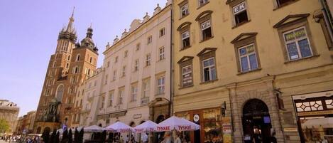 Rua com cafés ao ar livre, edifícios históricos e uma torre de igreja imponente.