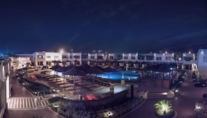 Resort com piscina, área de estar externa e calçada bem iluminada.