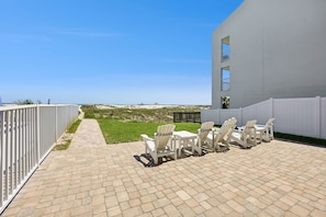 Um pátio com mobiliário externo e vista para a praia.