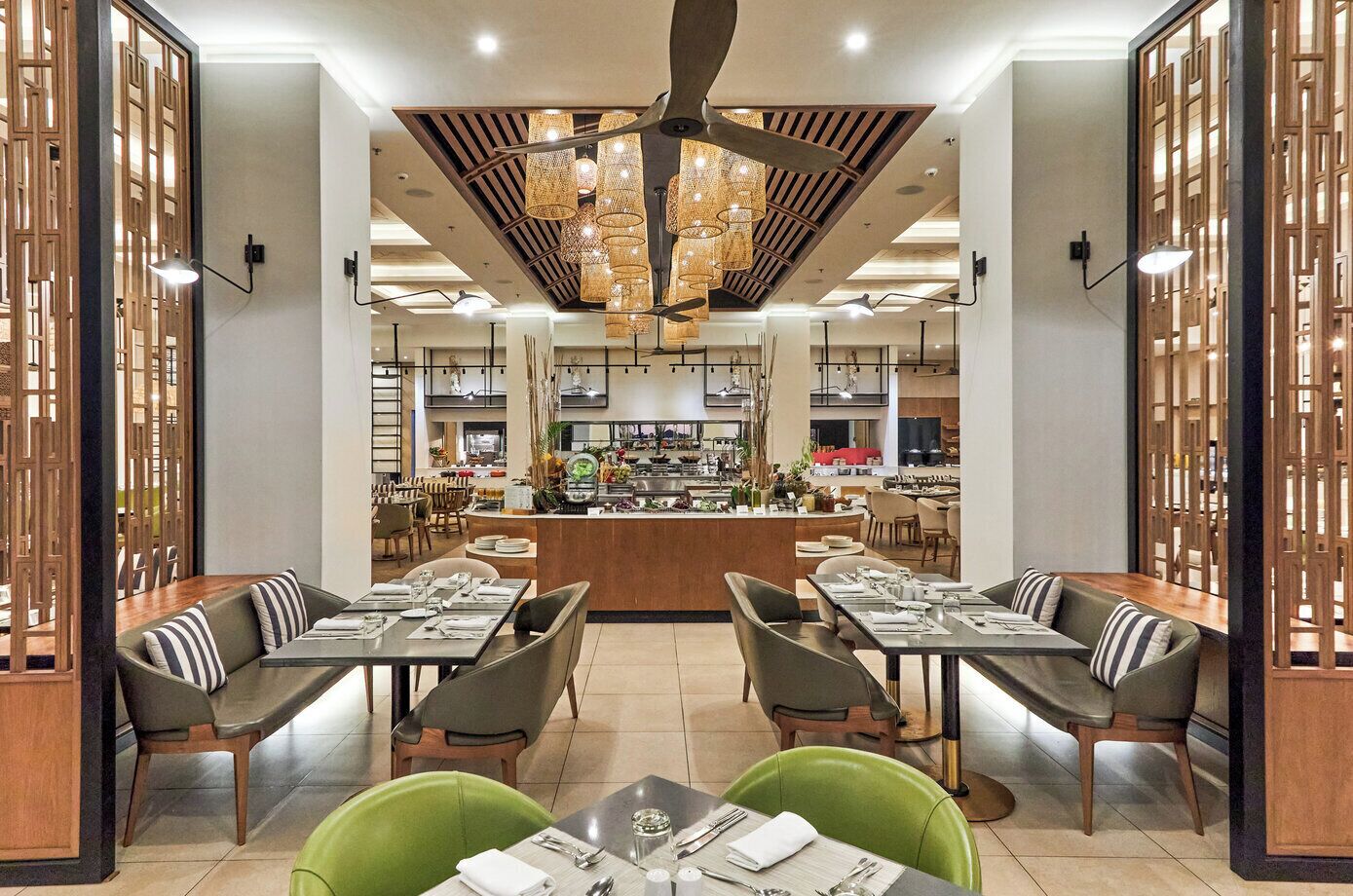 Um restaurante moderno com bar central, diversas áreas de estar e ventoinha no teto.