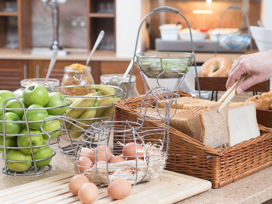 Um buffet de café da manhã com diversos alimentos, incluindo maçãs, ovos e pão.