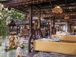 Restaurante com decoração em madeira, uma fonte e mesas preparadas para refeições.