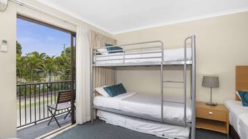 Quarto de hotel com varanda, uma cama, mesa de cabeceira e uma cadeira.