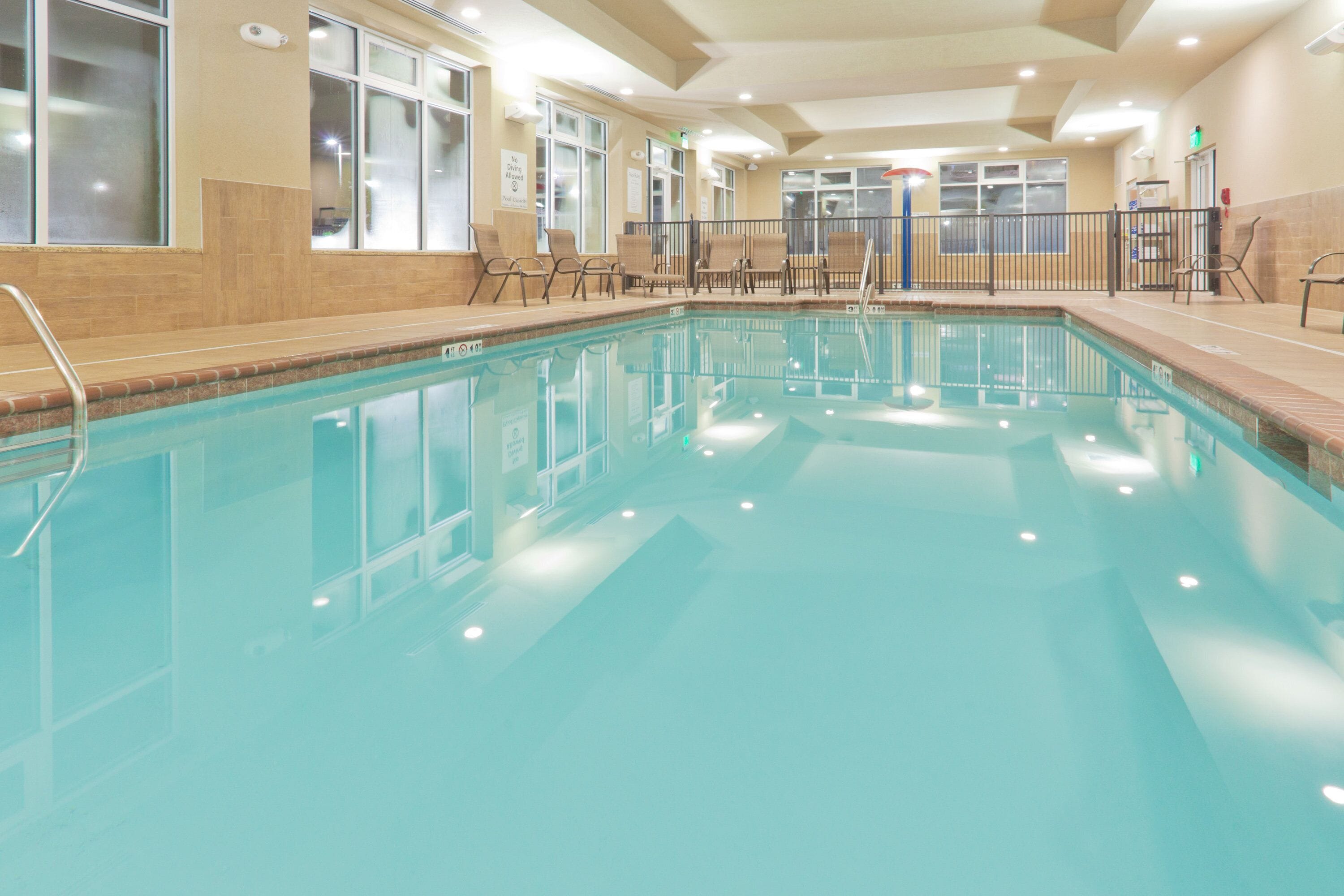 Piscina com água cristalina, rodeada por espreguiçadeiras e área de lazer.