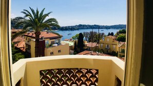 Varanda com vista para uma vila costeira, incluindo edifícios e uma palmeira.