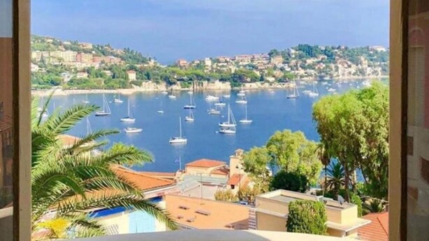 Uma cidade costeira com barcos na água, edifícios na orla e céu claro.