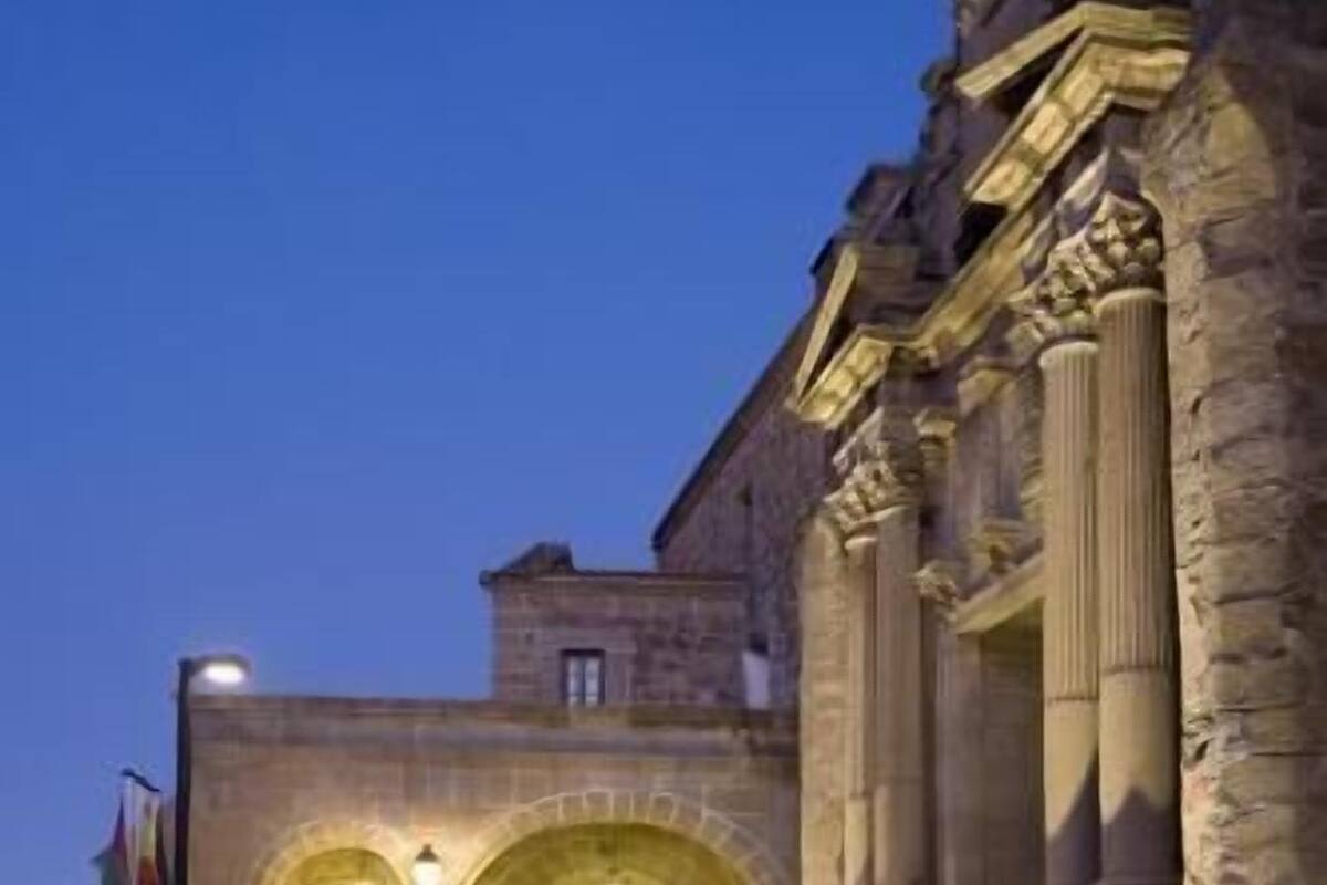 Um edifício histórico com fachada de pedra, entrada em arco e colunas clássicas.