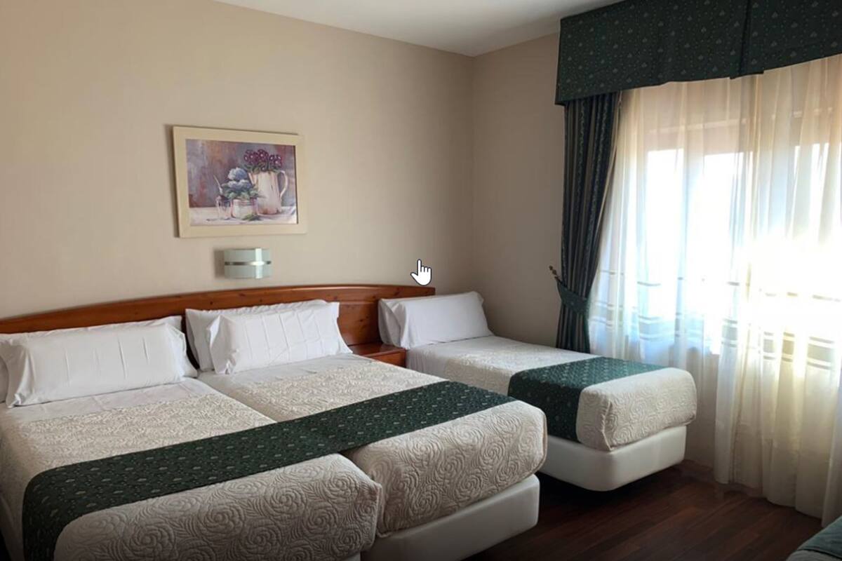 Quarto de hotel com duas camas, um quadro na parede e uma janela com cortinas.
