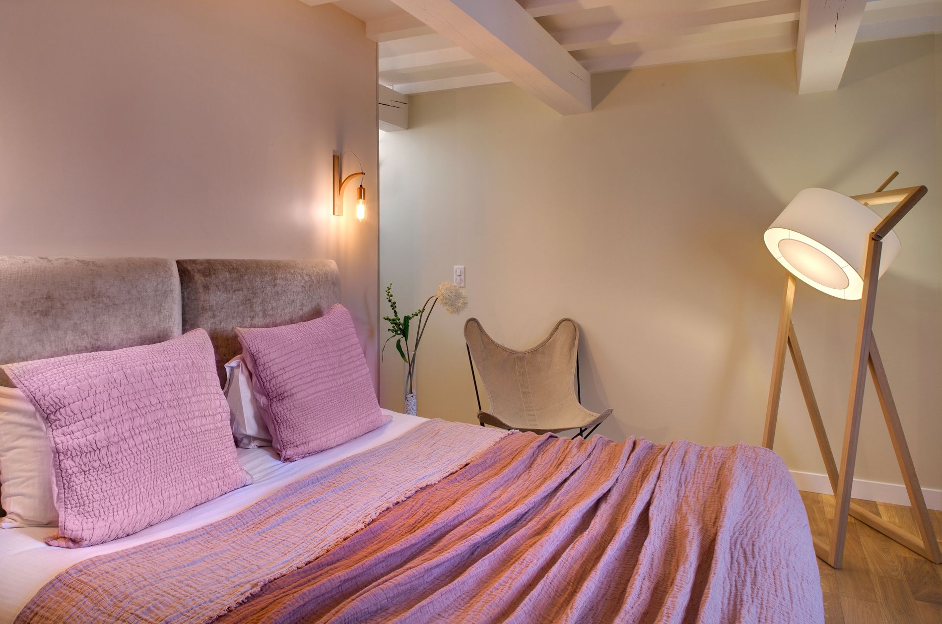 Quarto com cama, almofadas, abajur e luminária de chão.