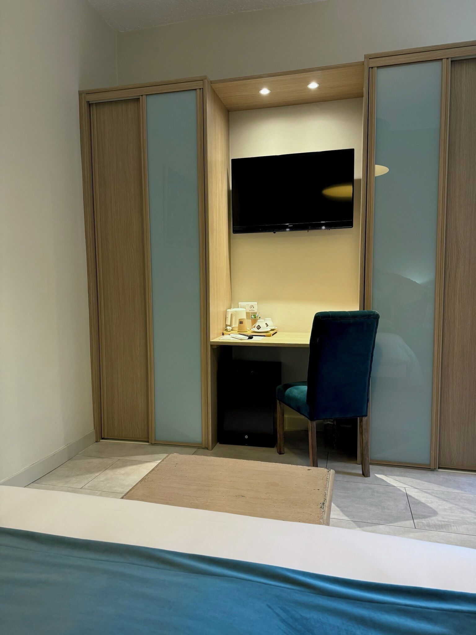Quarto com cama, escrivaninha, cadeira, televisão e guarda-roupa.