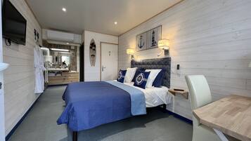 Quarto de hotel com uma cama, uma escrivaninha e um banheiro visível ao fundo.