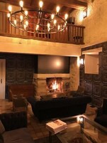 Uma sala de estar acolhedora com lareira, assentos confortáveis e um lustre moderno.