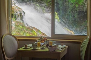 Mesa de café da manhã com vista para uma cachoeira através de uma janela.