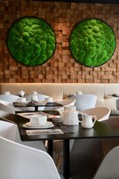 Uma sala de jantar com uma mesa posta para dois, uma parede de tijolos e duas decorações circulares verdes na parede.