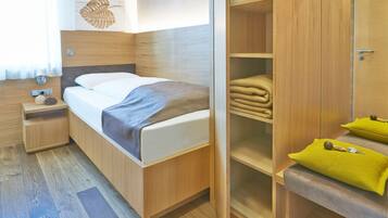 Quarto moderno com cama de madeira, mesa de cabeceira, guarda-roupa e um banco com toalhas.