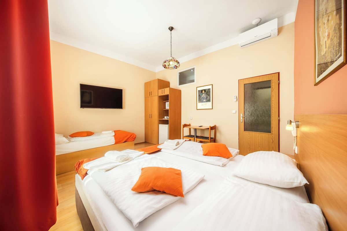 Quarto de hotel com uma cama grande, uma cama menor, uma escrivaninha e um guarda-roupa.