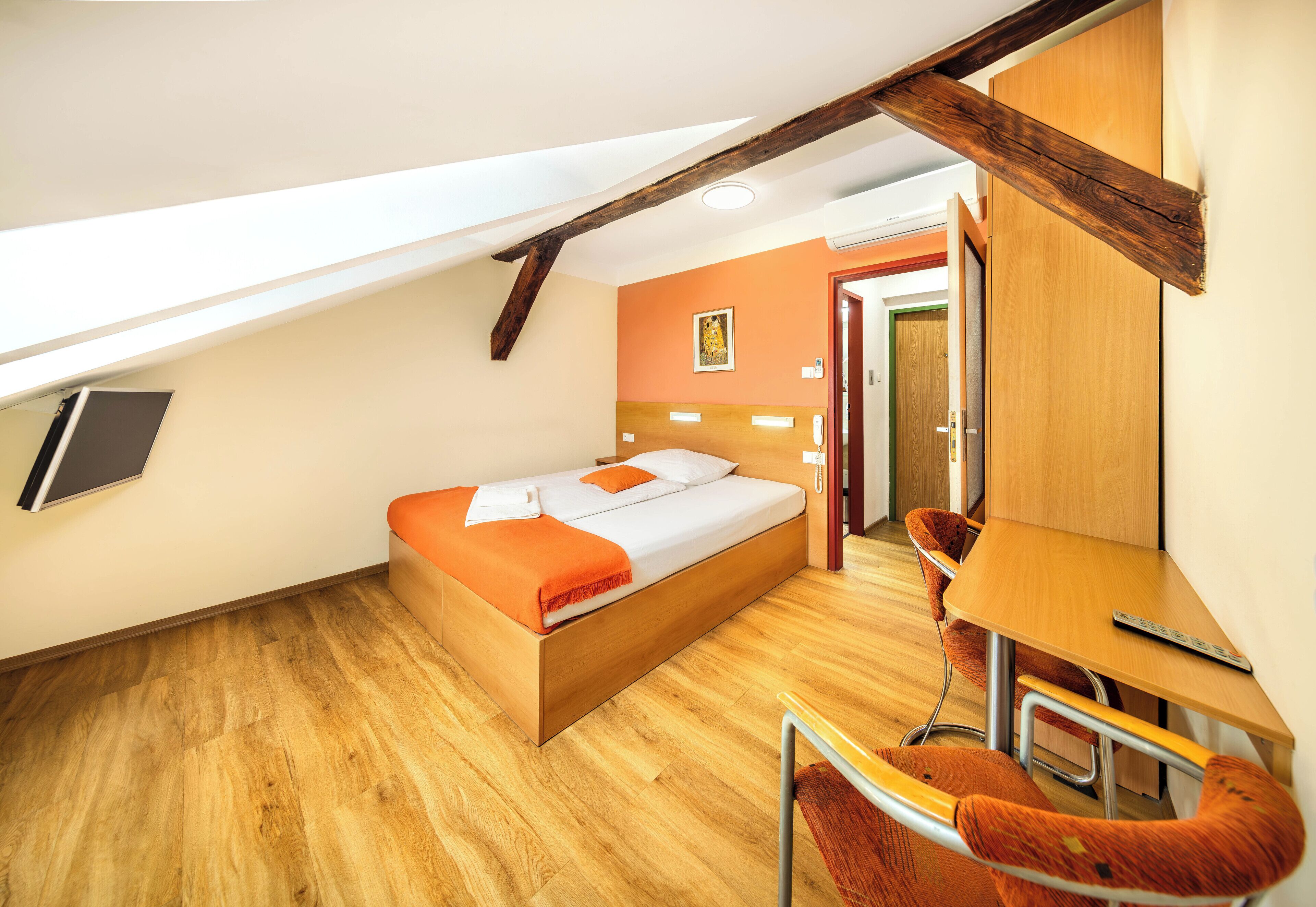 Quarto com cama de madeira, escrivaninha e cadeira.