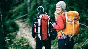 Duas pessoas caminhando em uma trilha florestal com mochilas.