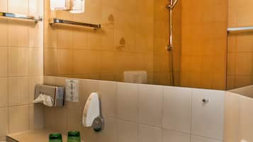 Uma casa de banho moderna com lavatório, espelho e chuveiro.