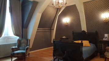 Quarto com cama, cadeira, candelabro e papel de parede estampado.
