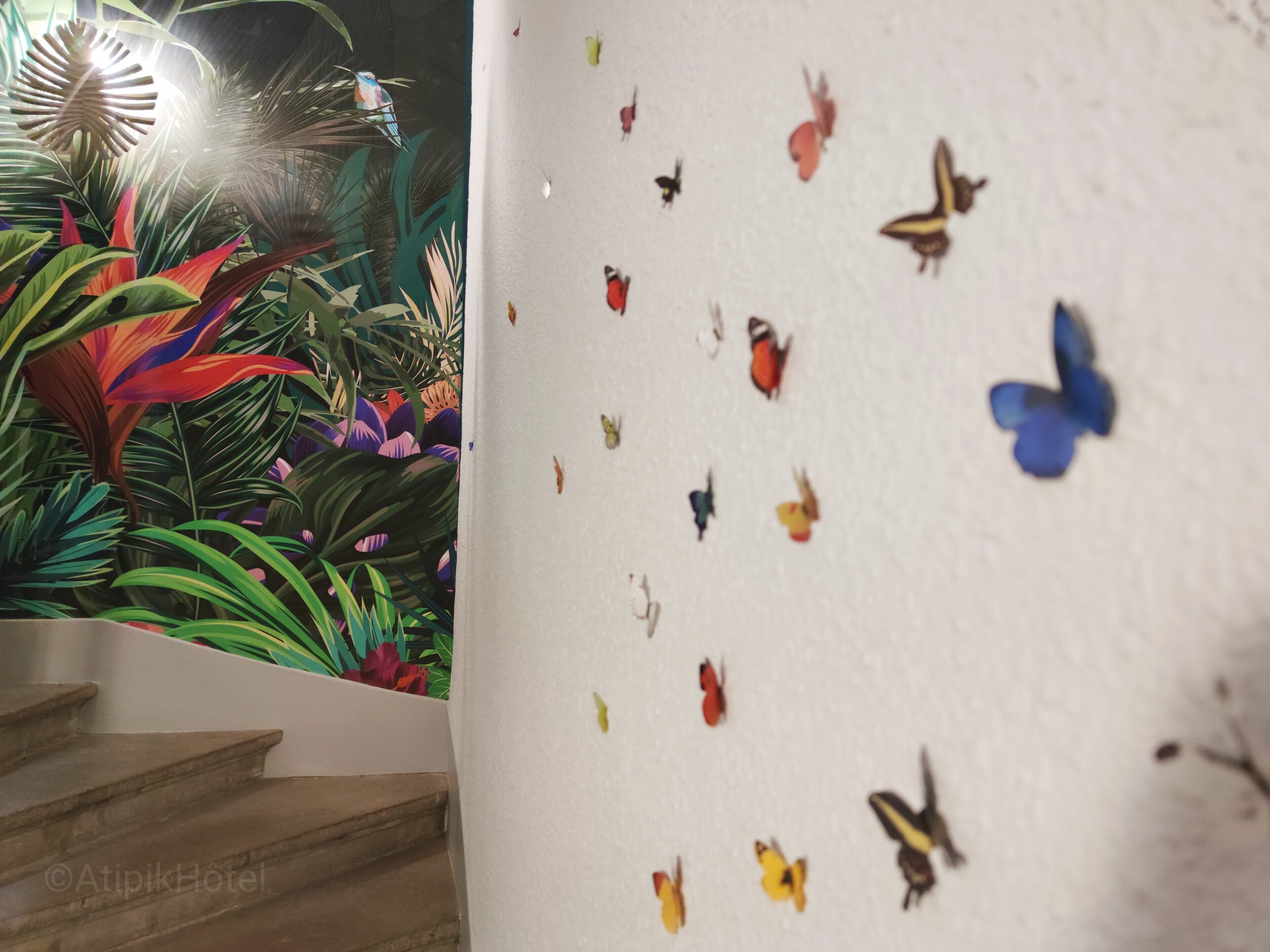 Uma escada com uma parede decorada com adesivos de borboletas coloridas.