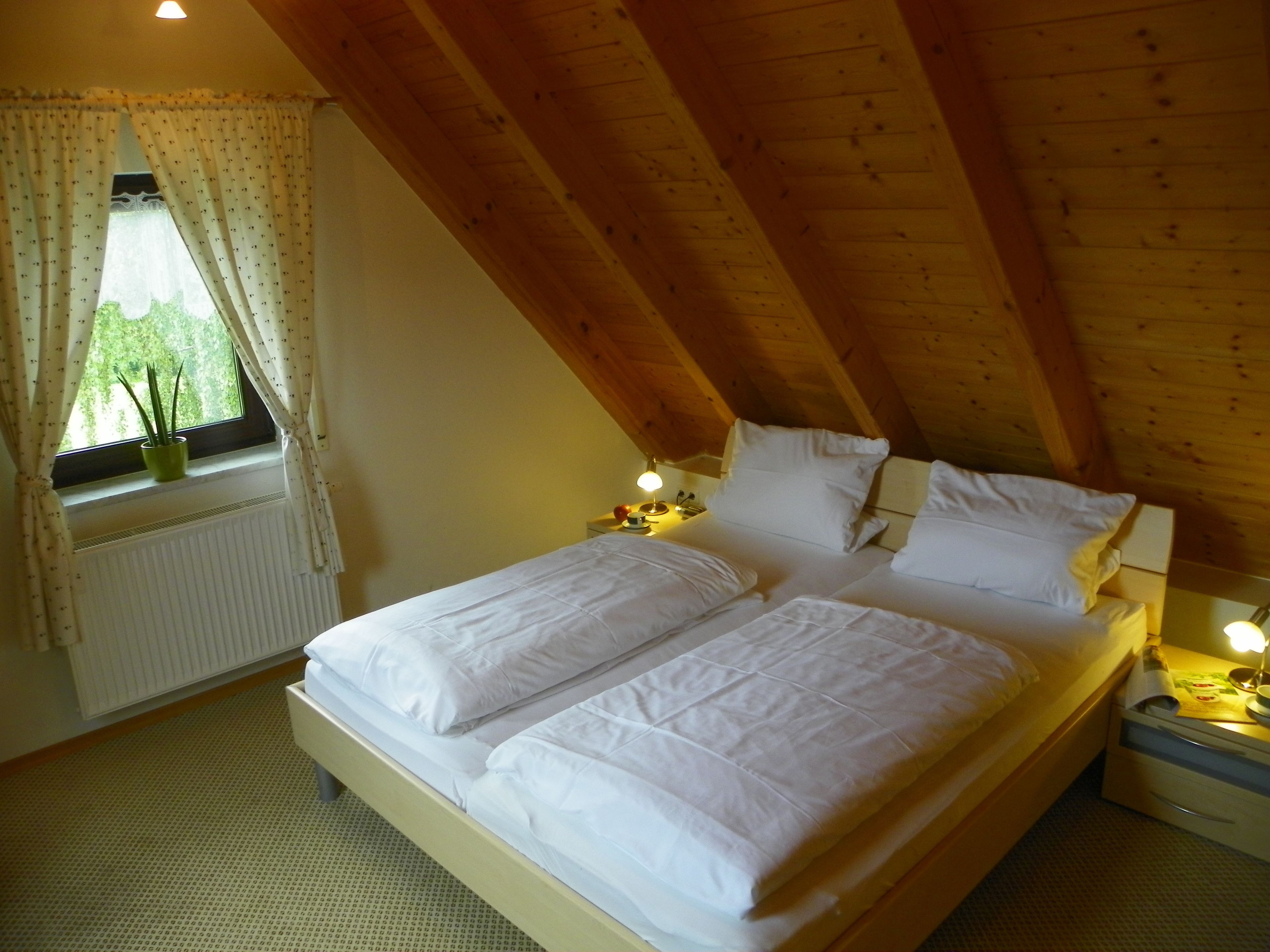 Um quarto com uma cama, uma janela com cortinas, uma mesa de cabeceira e um abajur.