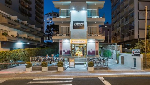 Um edifício moderno com uma placa 'parafro', entrada de supermercado, área de estar ao ar livre e entrada bem iluminada.