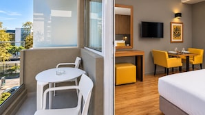 Quarto de hotel moderno com varanda, área de refeições, cama e televisão.