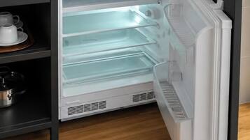 Uma cozinha moderna com frigorífico embutido, chaleira e uma estante com chávenas.