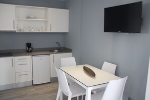 Uma cozinha moderna com armários brancos, cafeteira e mesa de jantar com cadeiras.