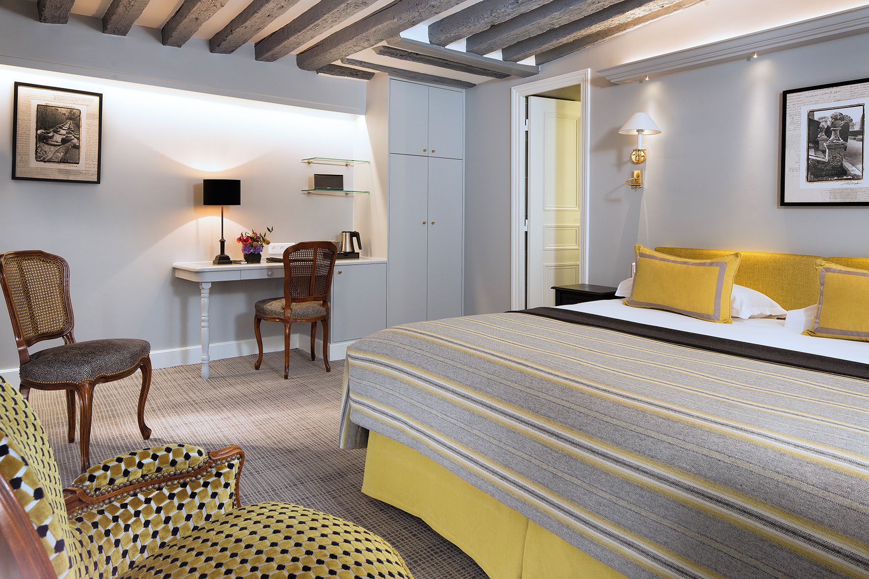 Quarto de hotel com cama, escrivaninha, cadeira e sofá. Há uma janela e uma porta.