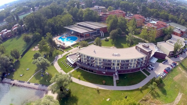 Vista aérea de um campus com um edifício circular central, piscina e áreas verdes ao redor.
